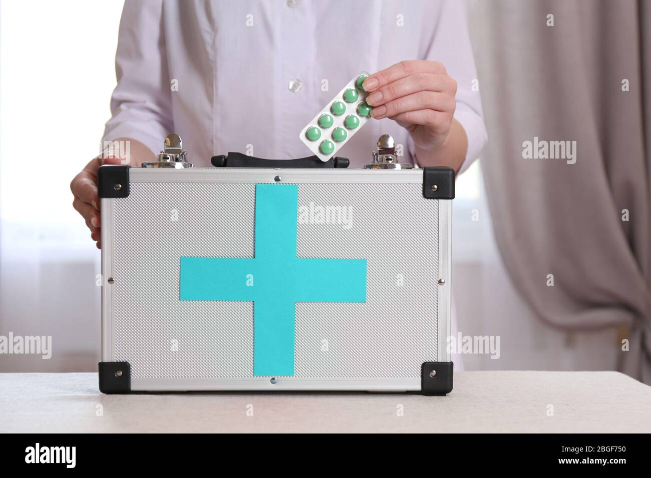 Nurse holding first aid kit in room Stock Photo - Alamy