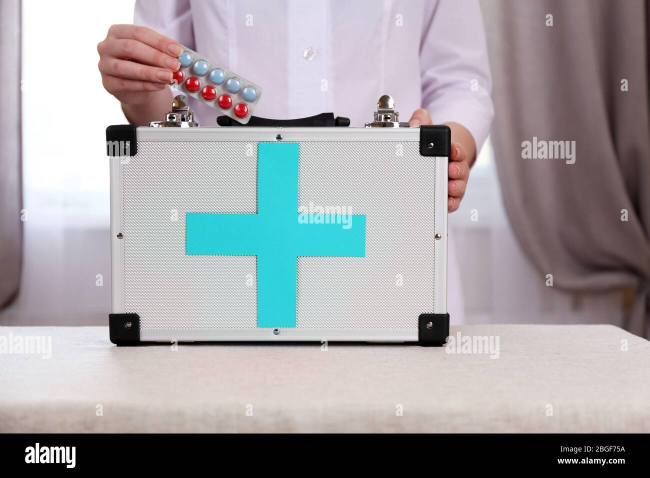 Nurse holding first aid kit in room Stock Photo - Alamy