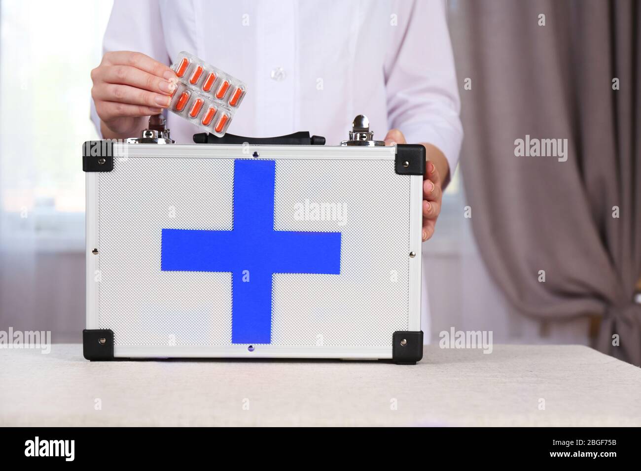 Nurse holding first aid kit in room Stock Photo - Alamy