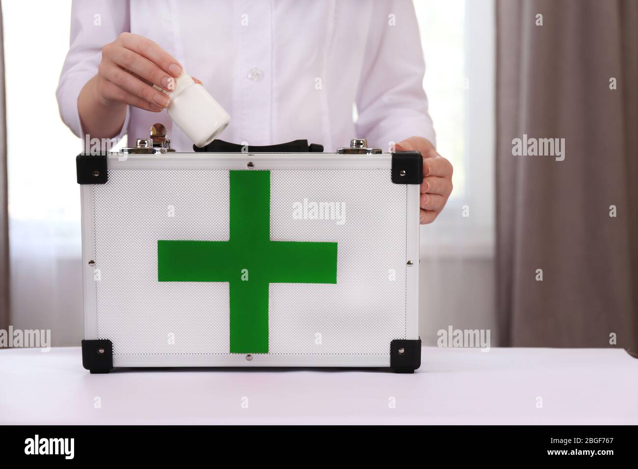 Nurse holding first aid kit in room Stock Photo - Alamy