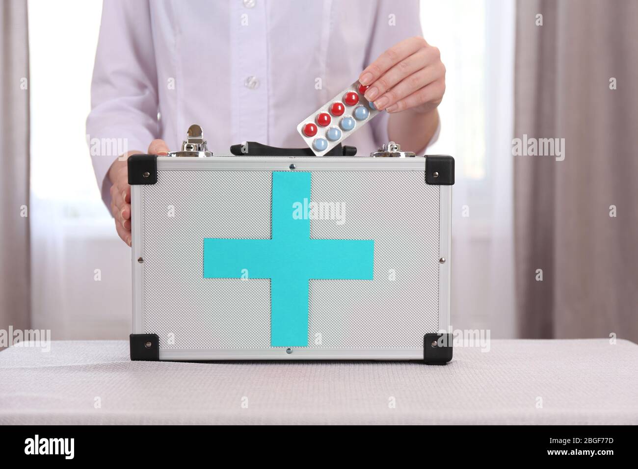 Nurse holding first aid kit in room Stock Photo - Alamy