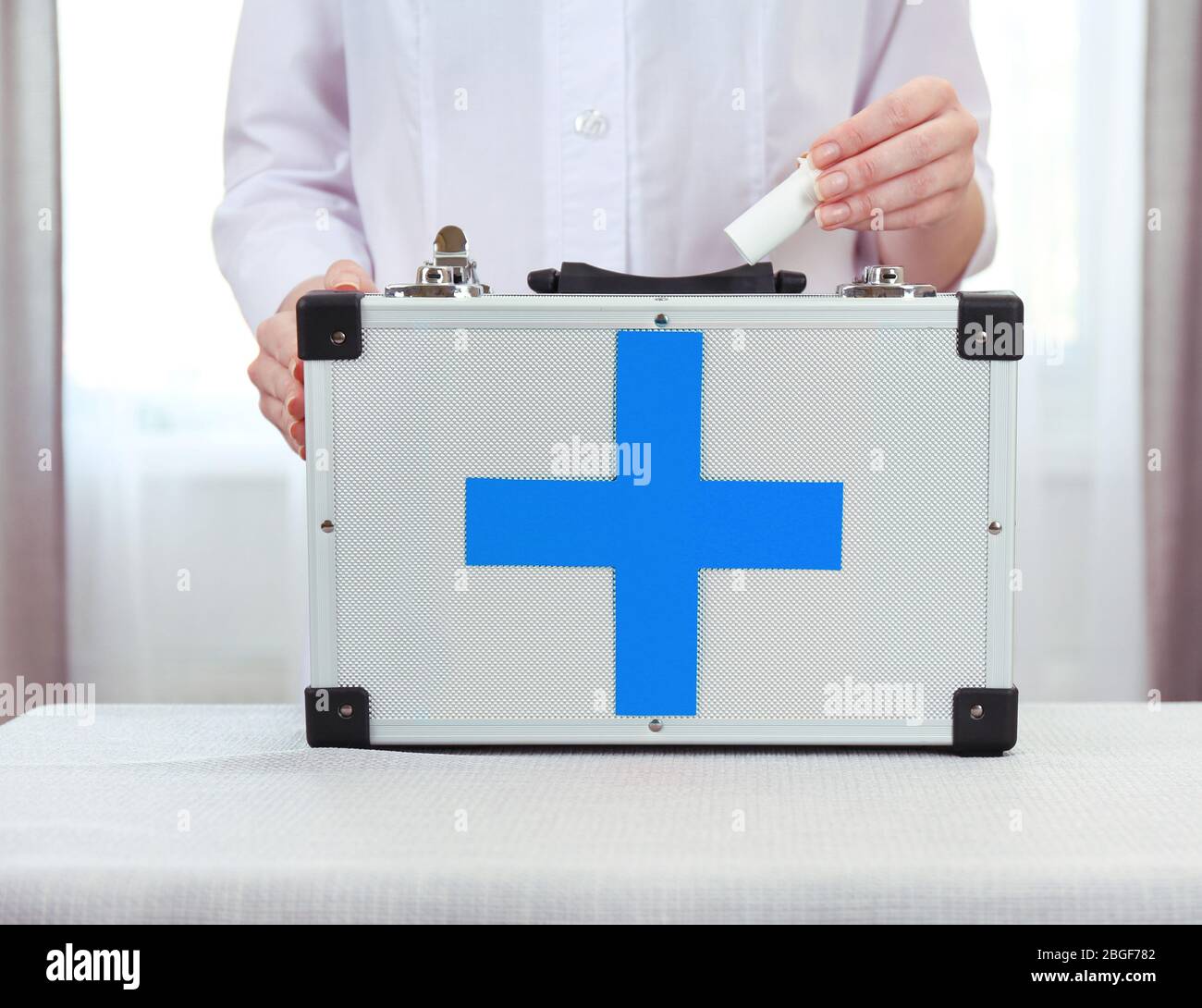 Nurse holding first aid kit in room Stock Photo - Alamy