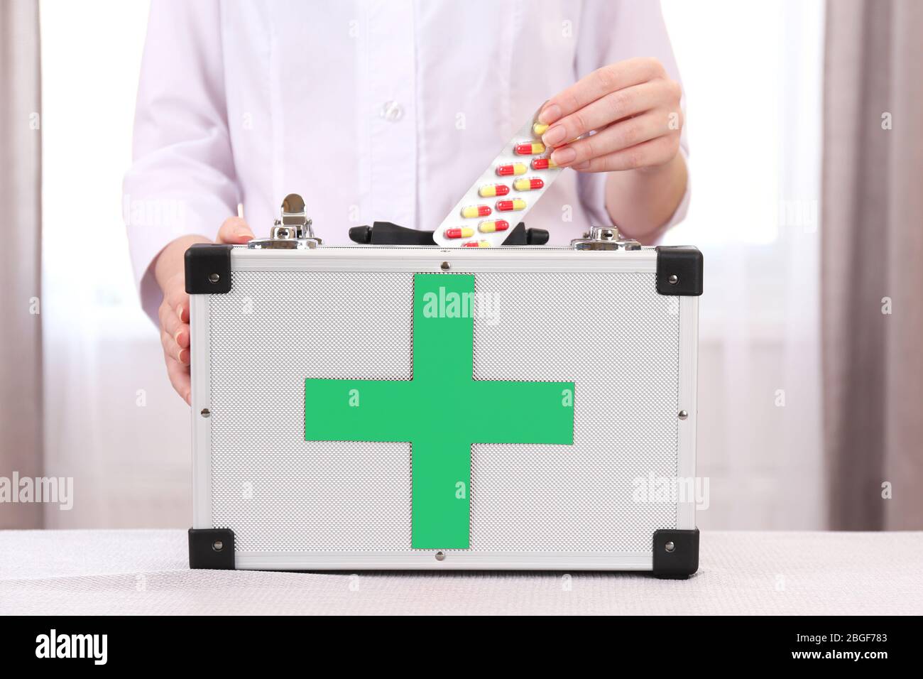 Nurse holding first aid kit in room Stock Photo - Alamy