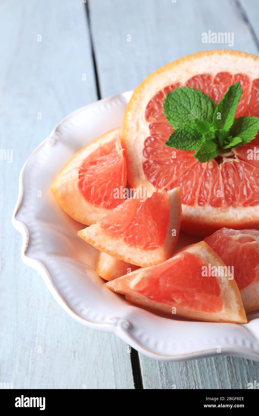 Ripe grapefruits on plate on color wooden background Stock Photo - Alamy