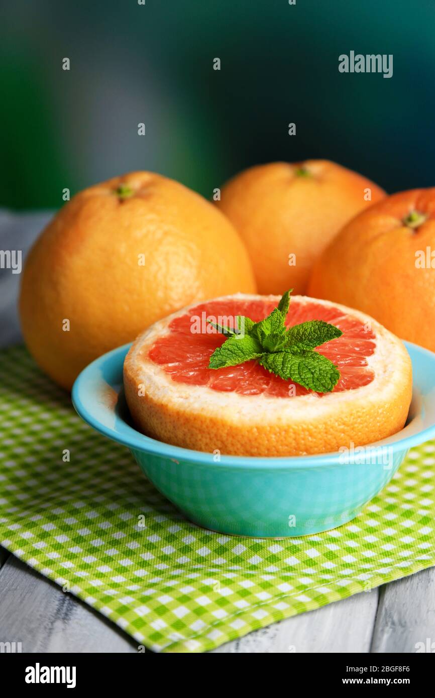 Ripe grapefruits in bowl on color wooden table, on bright background ...