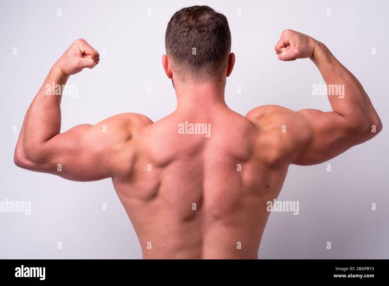 Rear view of muscular man flexing both arms shirtless Stock Photo - Alamy