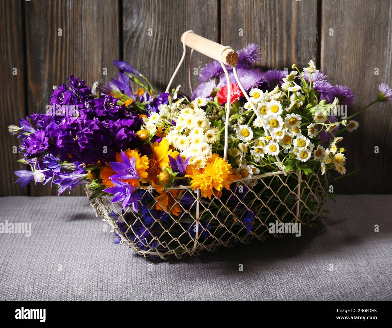 Beautiful wild flowers in basket on wooden background Stock Photo - Alamy