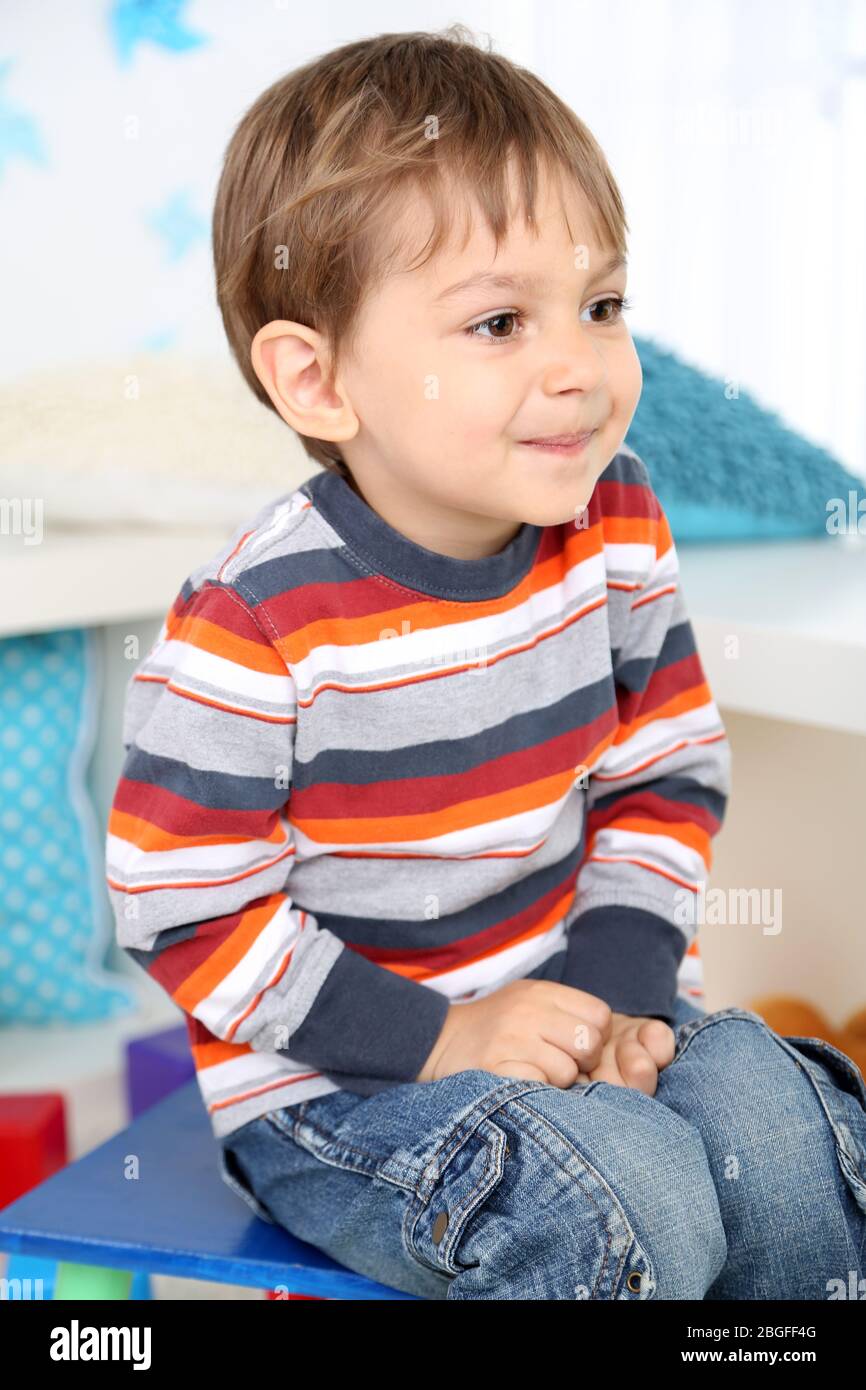 Cute little boy sitting on small chair in room Stock Photo - Alamy