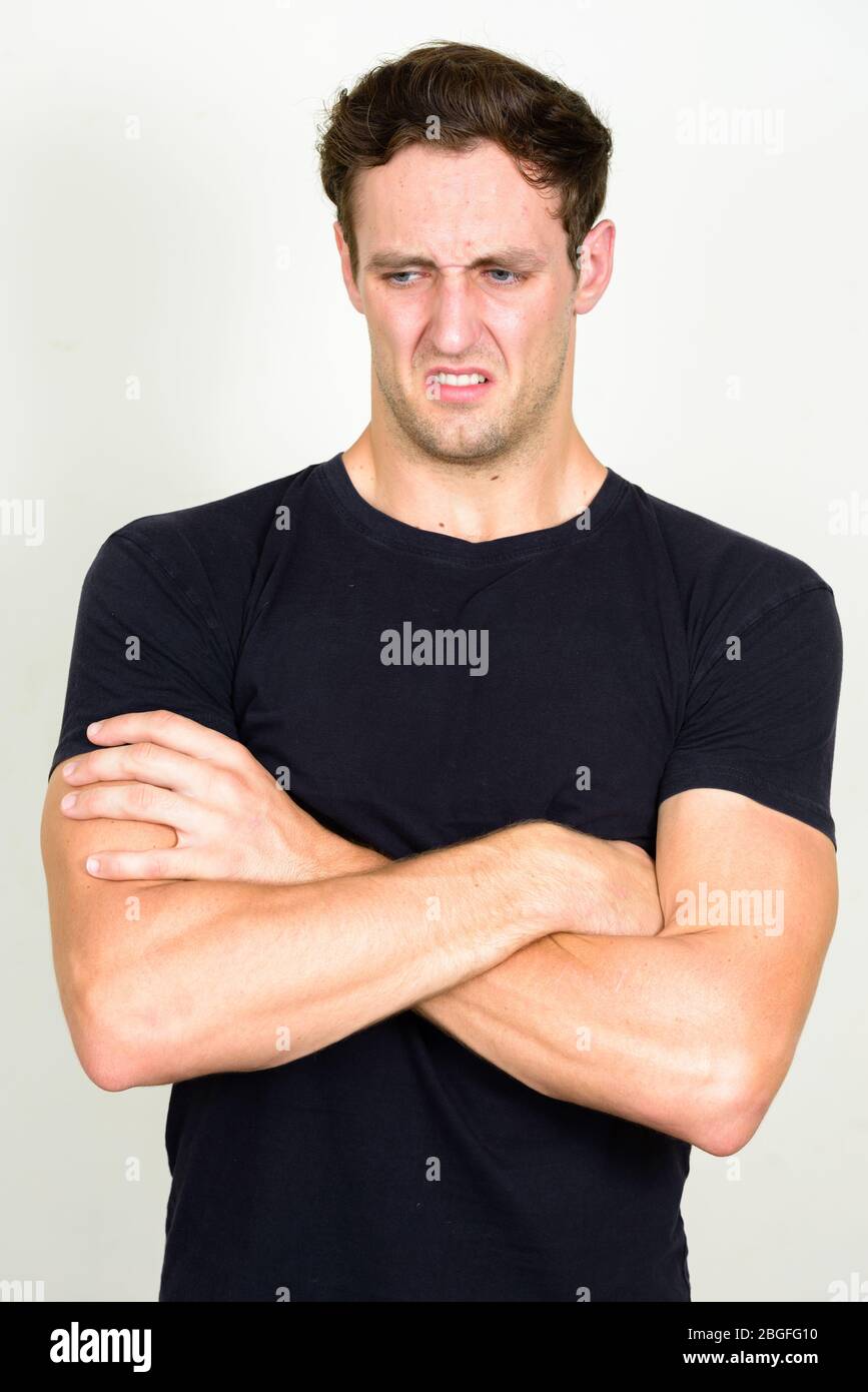 Portrait of stressed young man looking disgusted with arms crossed ...