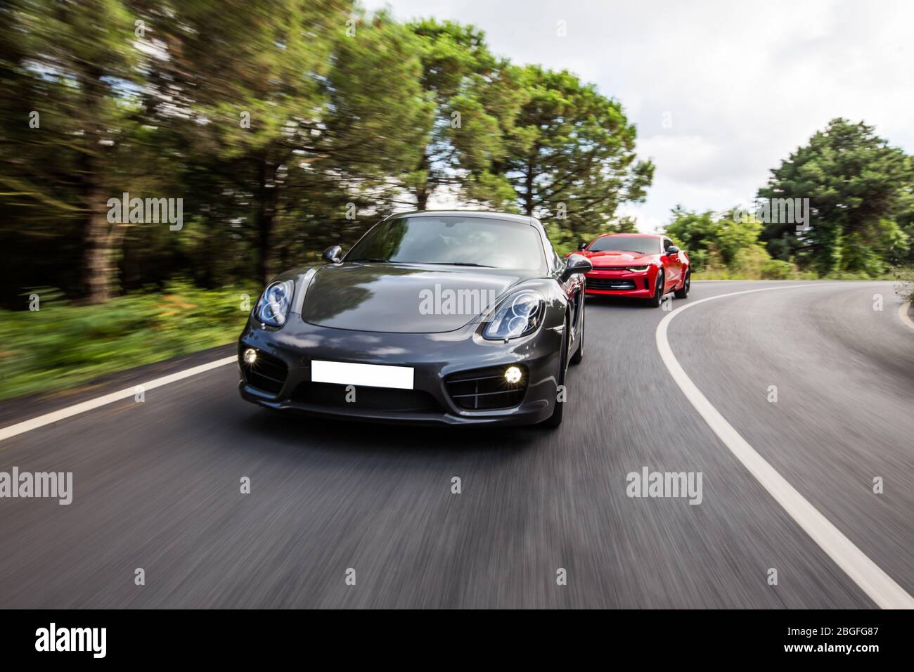 Silver car and red one behind racing Stock Photo - Alamy