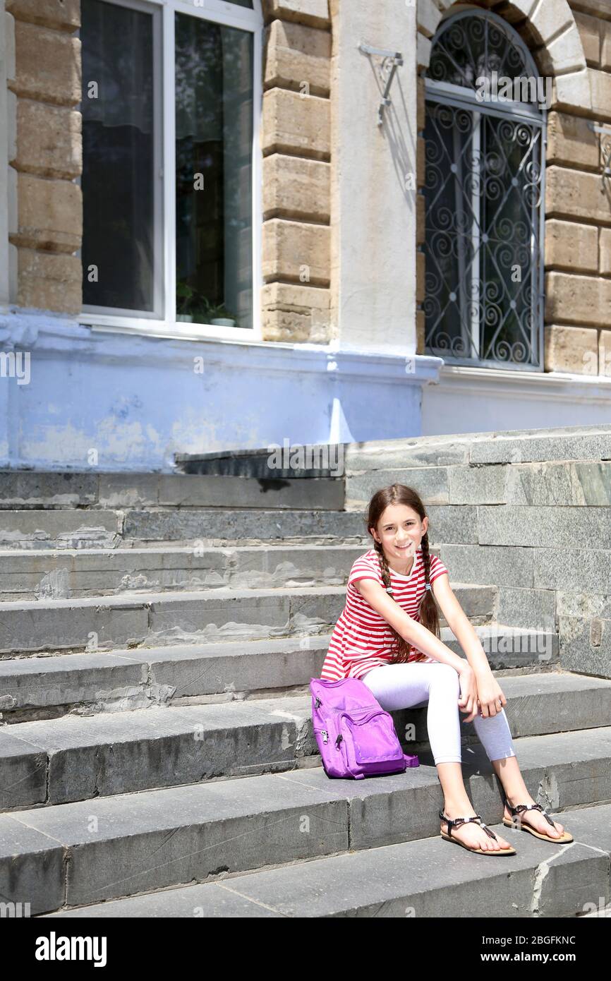 Cute girl with backpack on the steps outside Stock Photo - Alamy