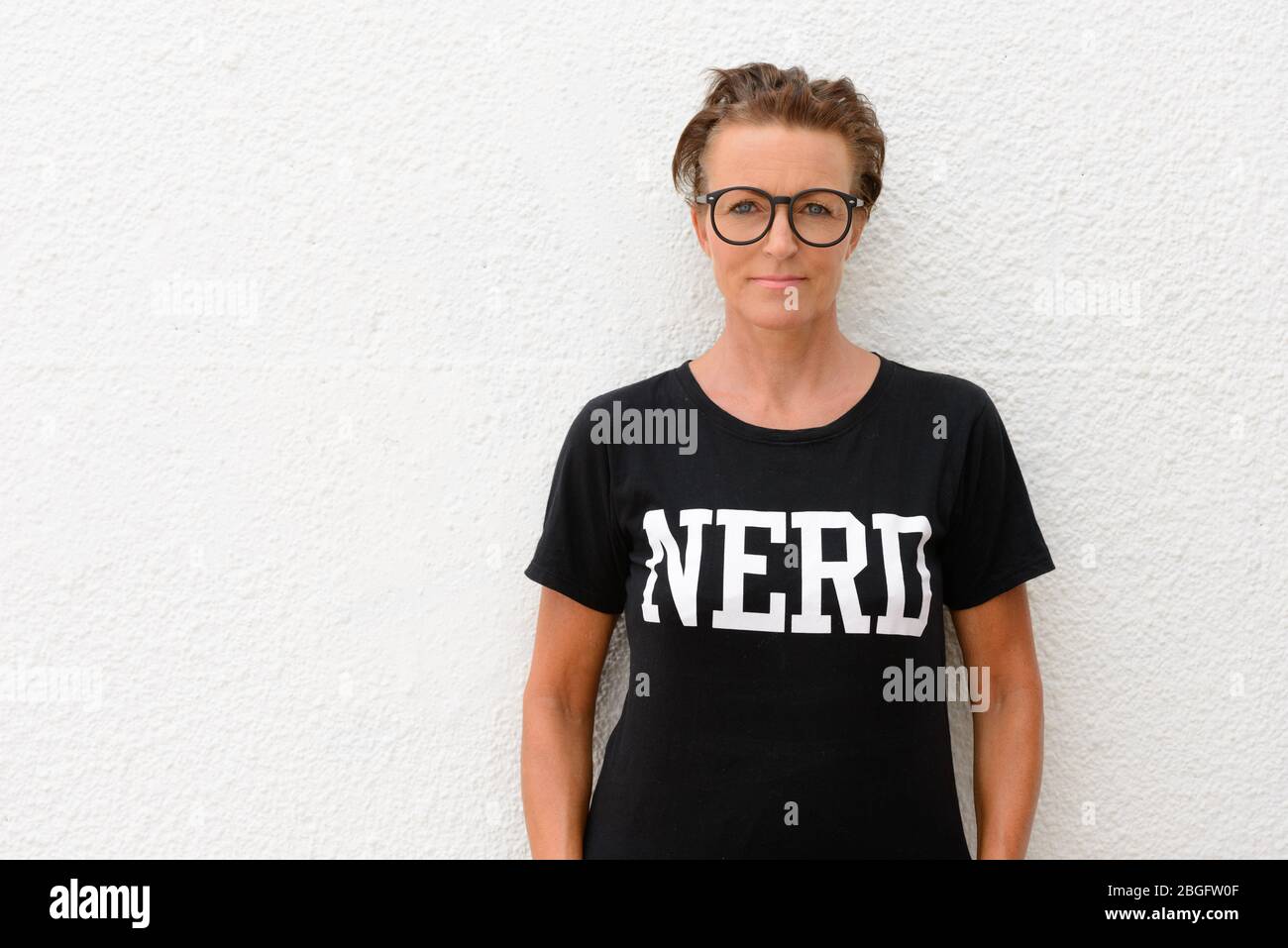 Mature nerd woman wearing big eyeglasses and standing against white ...