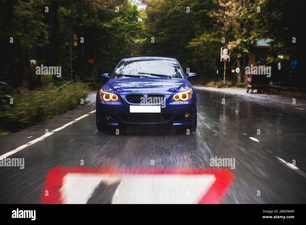 Blue car high speed drive on the forest road in a stormy rainy day ...