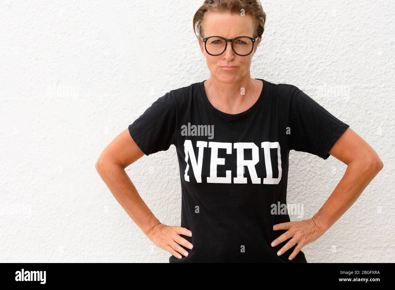 Angry mature nerd woman wearing big eyeglasses and standing against ...