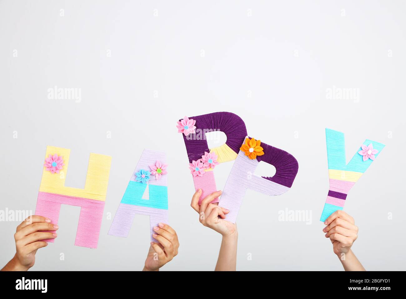 Hands holding up letters building word happy on grey background Stock ...