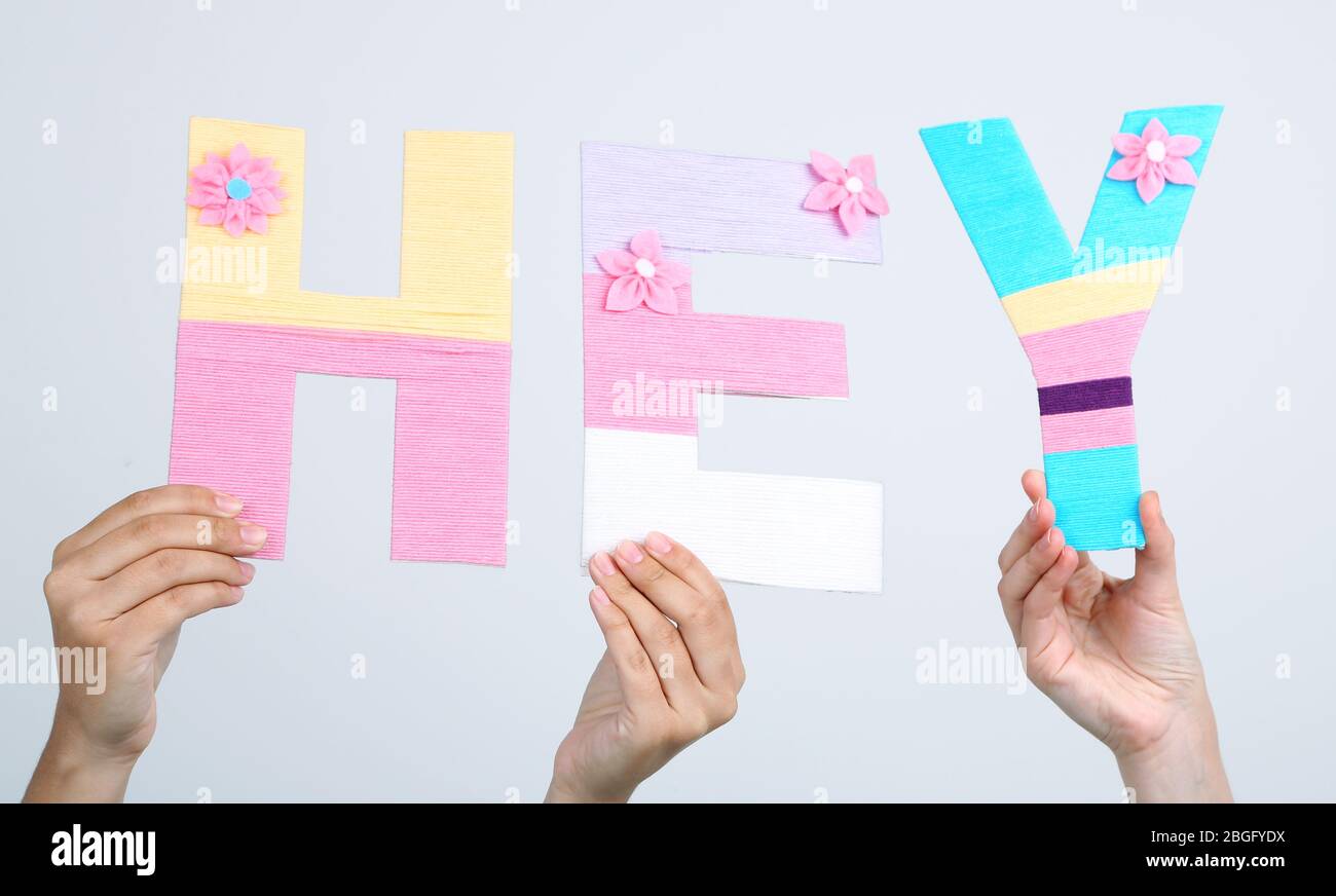 Hands holding up letters building word hey on grey background Stock ...