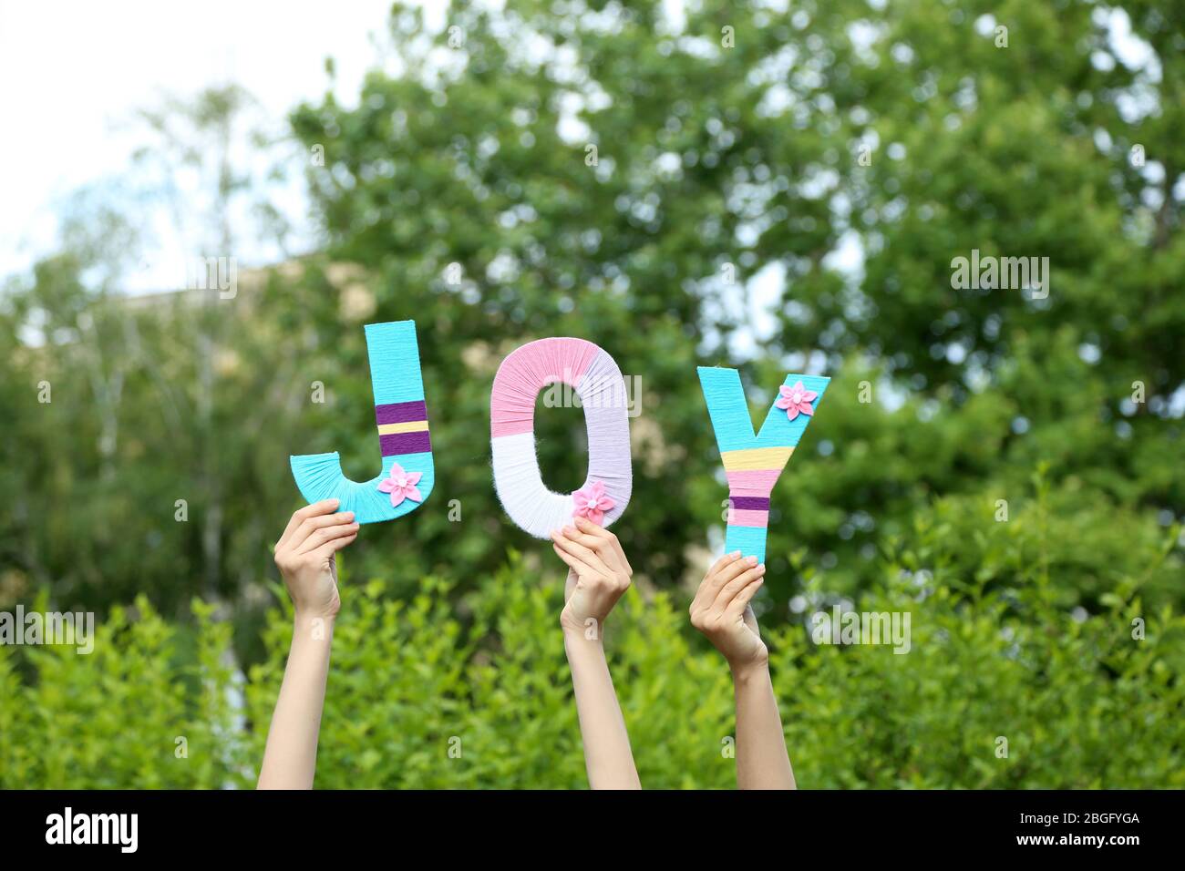 Hands holding up letters building word Joy on natural background Stock ...