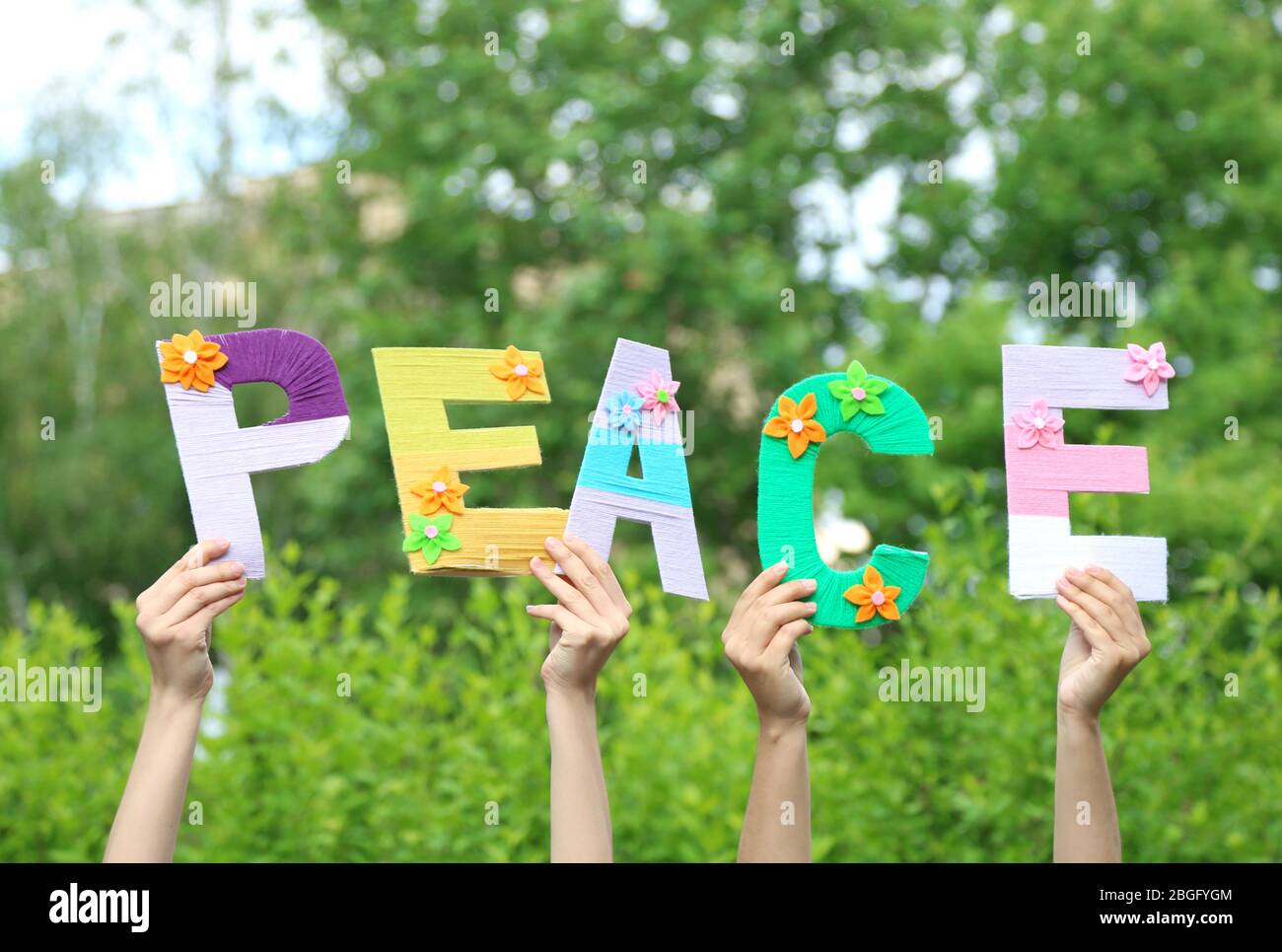 Hands holding up letters building word peace on natural background ...