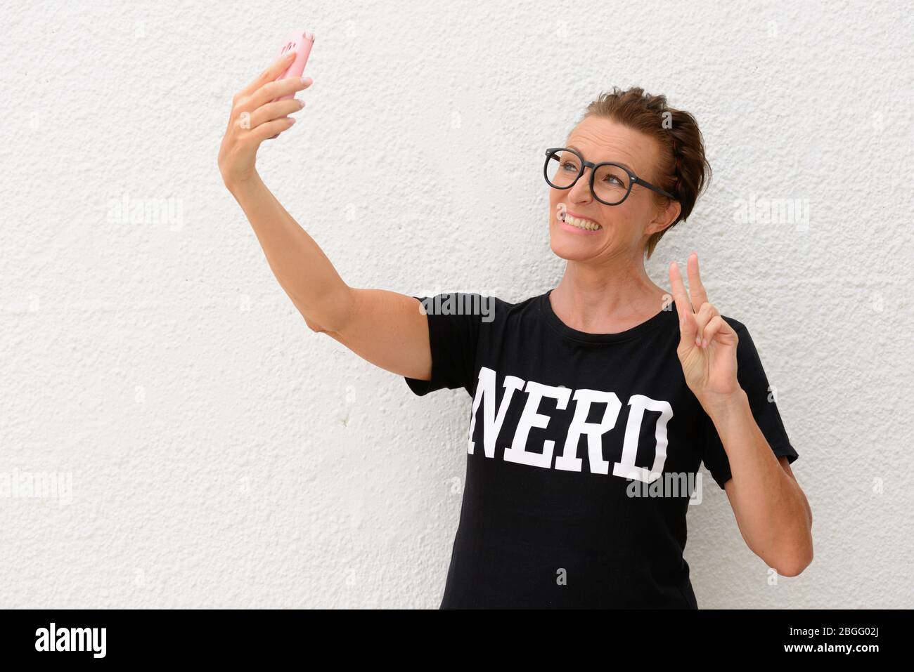 Mature nerd woman wearing big eyeglasses and standing against white ...