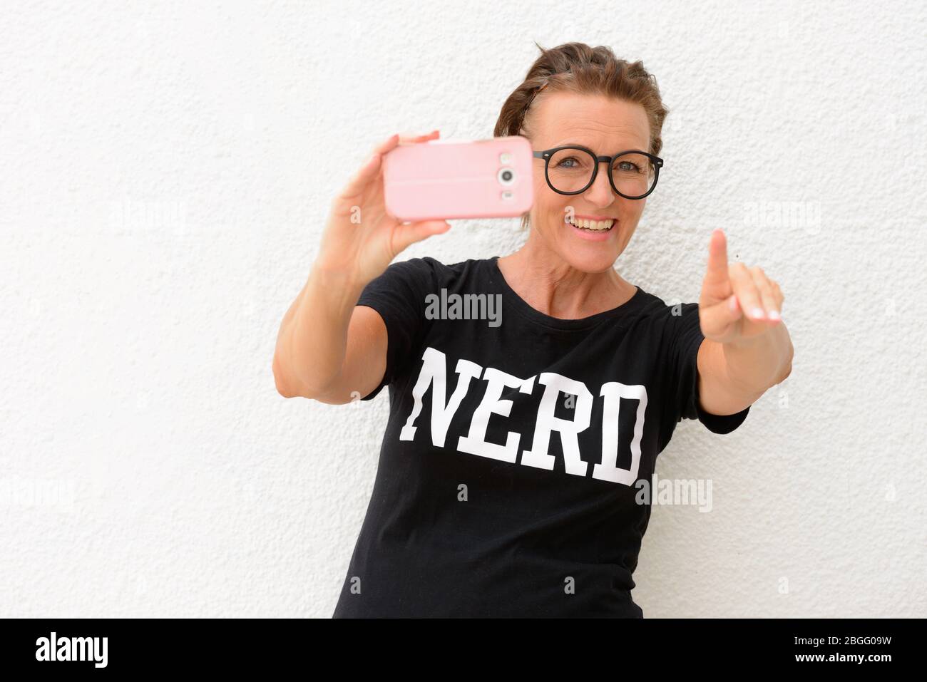 Happy mature nerd woman wearing big eyeglasses and standing against ...