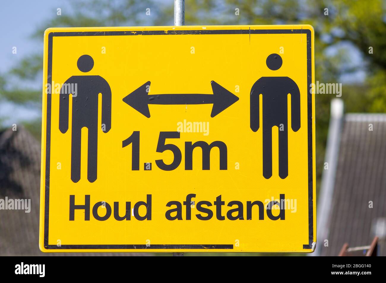 Yellow warning sign with the text in dutch: 1.5 meter, keep distance ...