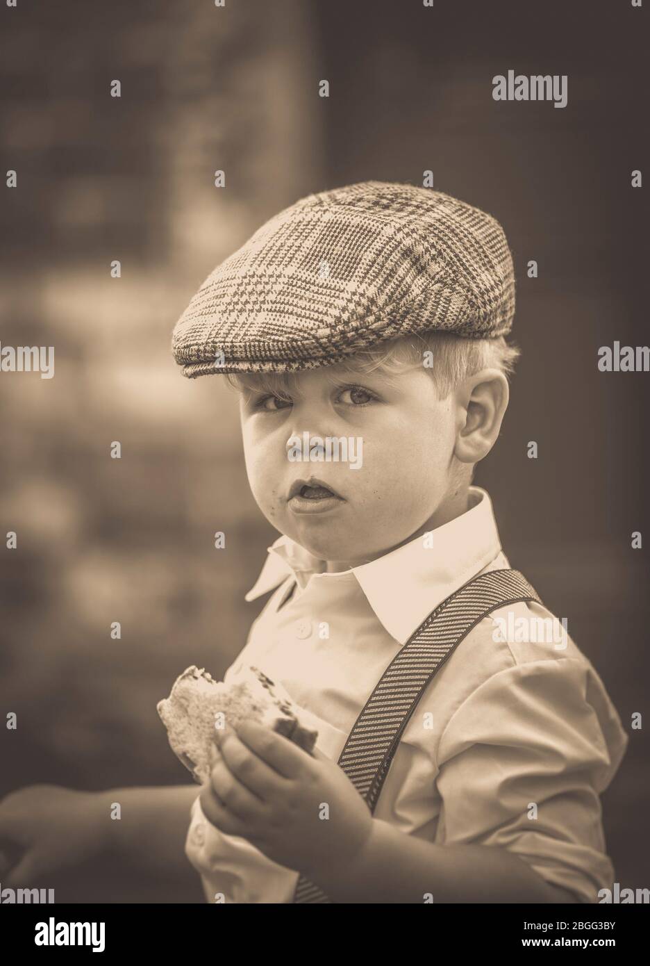 Sepia close up of 1940s, ww2 little boy in vintage flat cap & braces ...