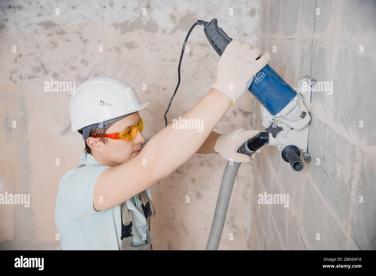 Builder worker cutting electrical chase in concrete wall with ...
