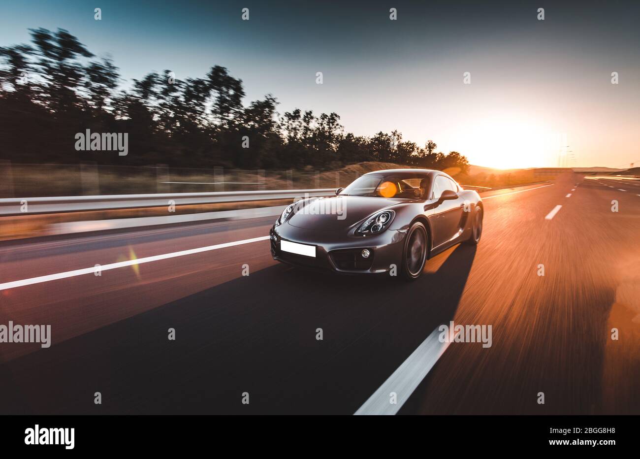 Navy blue sport car speed drive on the autobahn under the sunlight ...