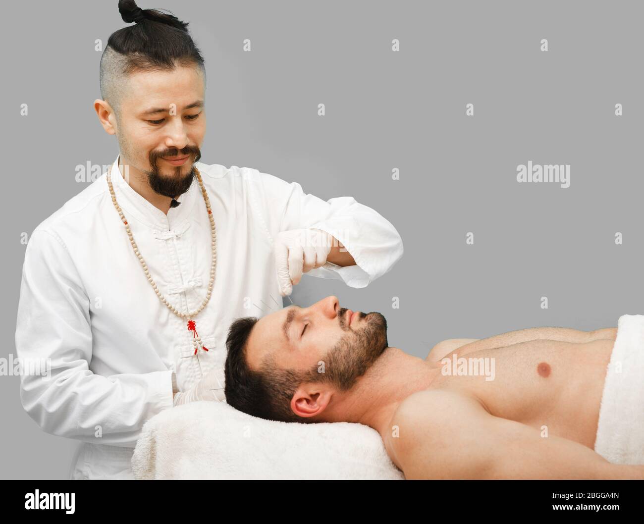 Man enjoys the acupuncture procedure. Acupuncturist doing acupuncture ...