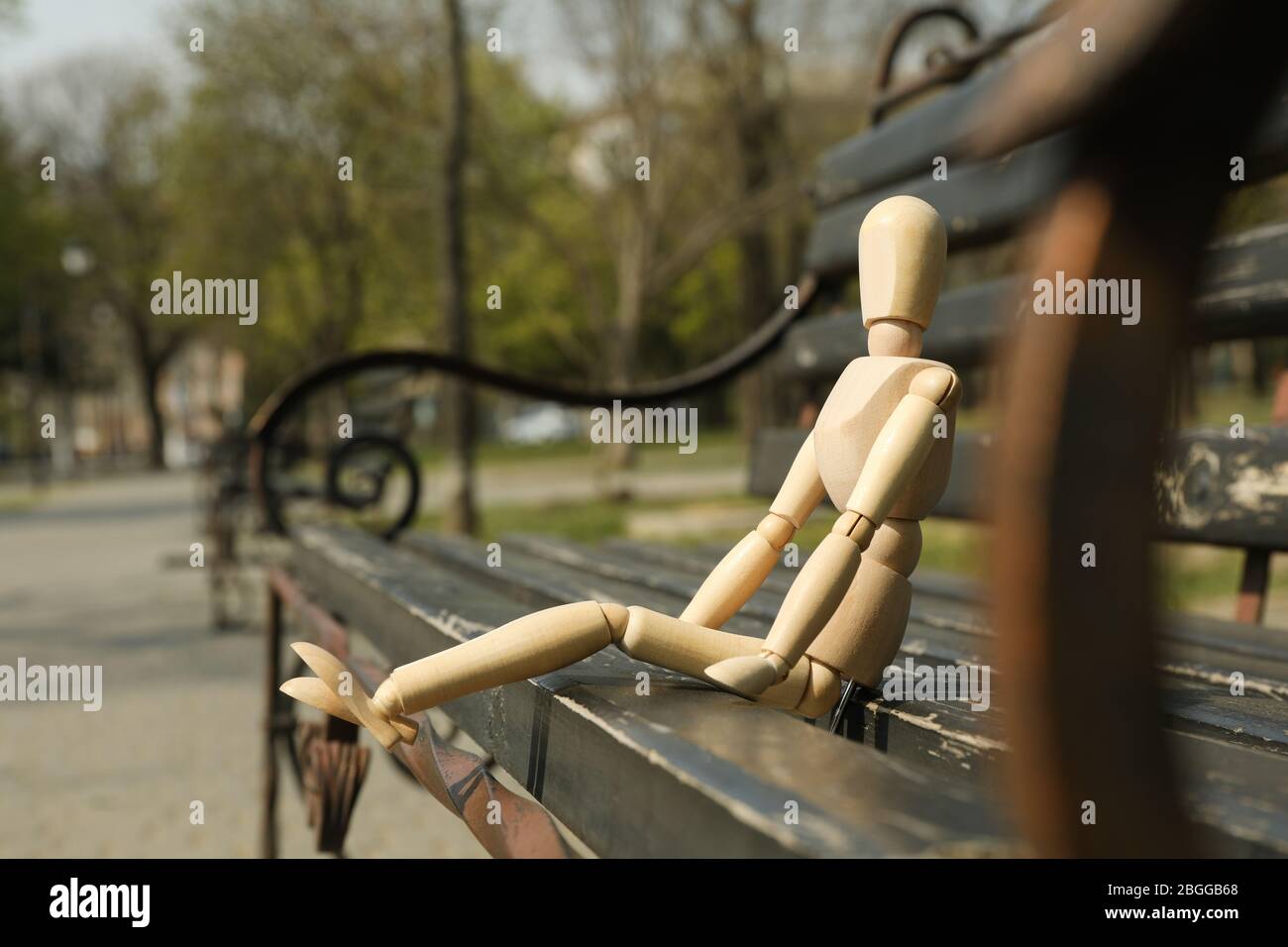 Wooden man sits on bench. Spring day Stock Photo - Alamy