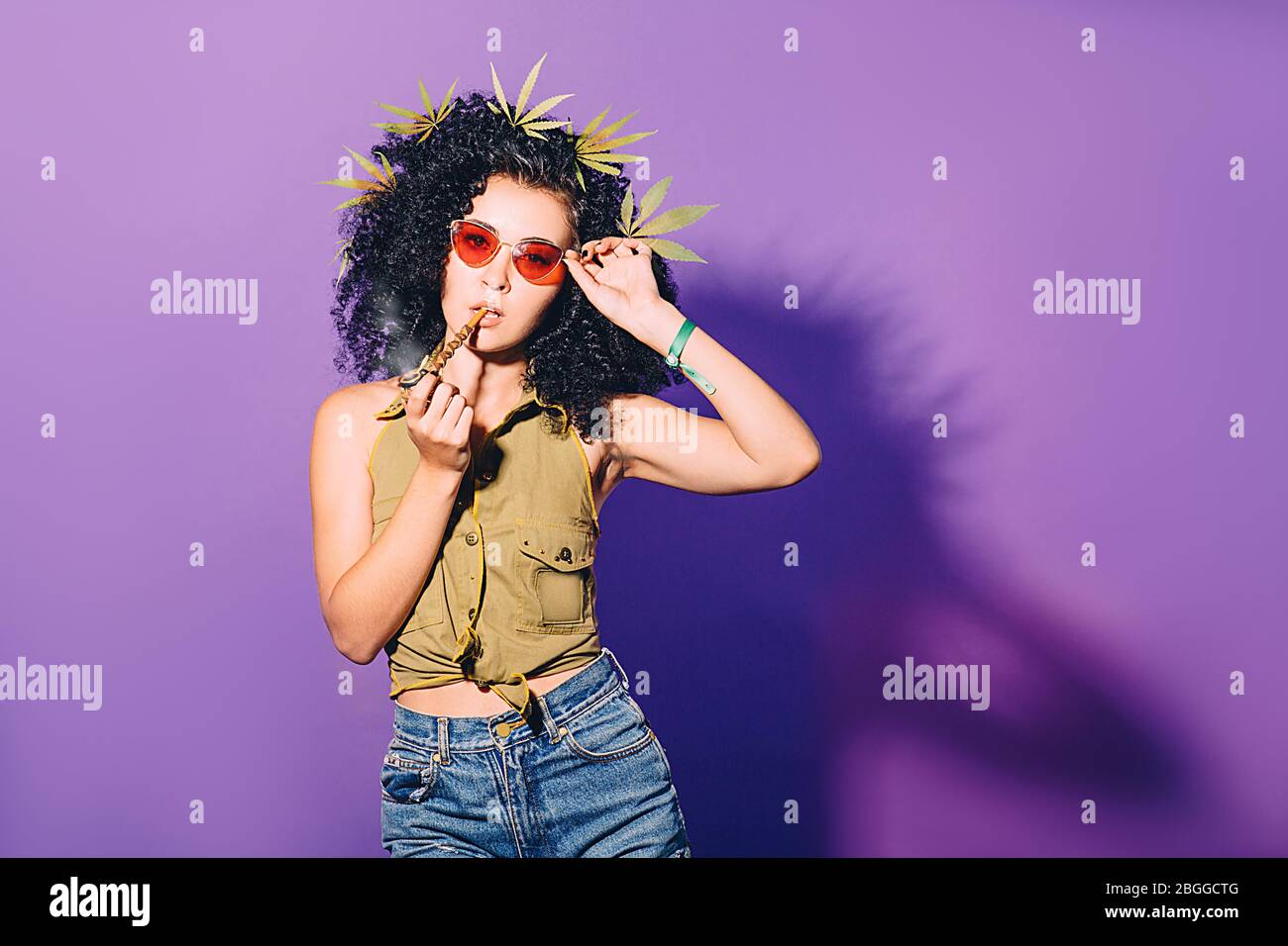 Hipster woman smokes marijuana through a special smoking pipe. A woman ...