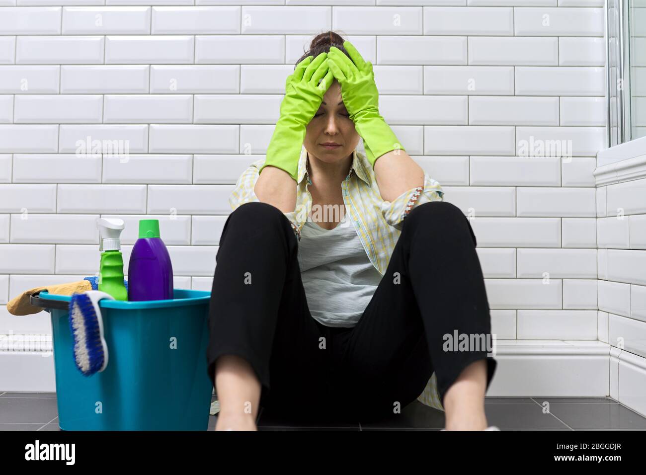 Tired woman doing house cleaning in bathroom. Female in gloves with ...