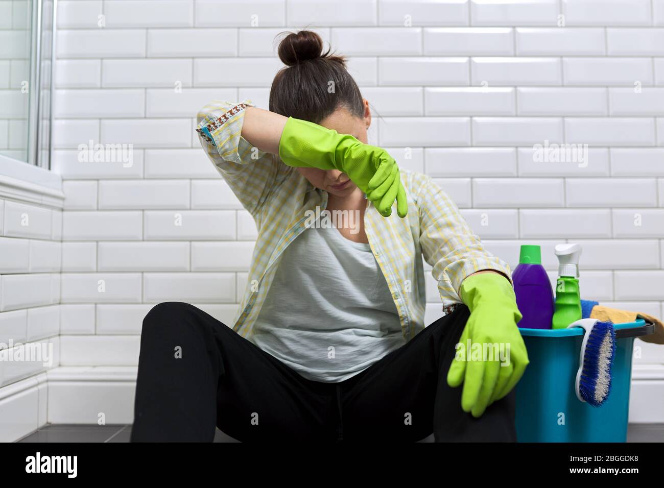 Tired woman doing house cleaning in bathroom. Female in gloves with ...