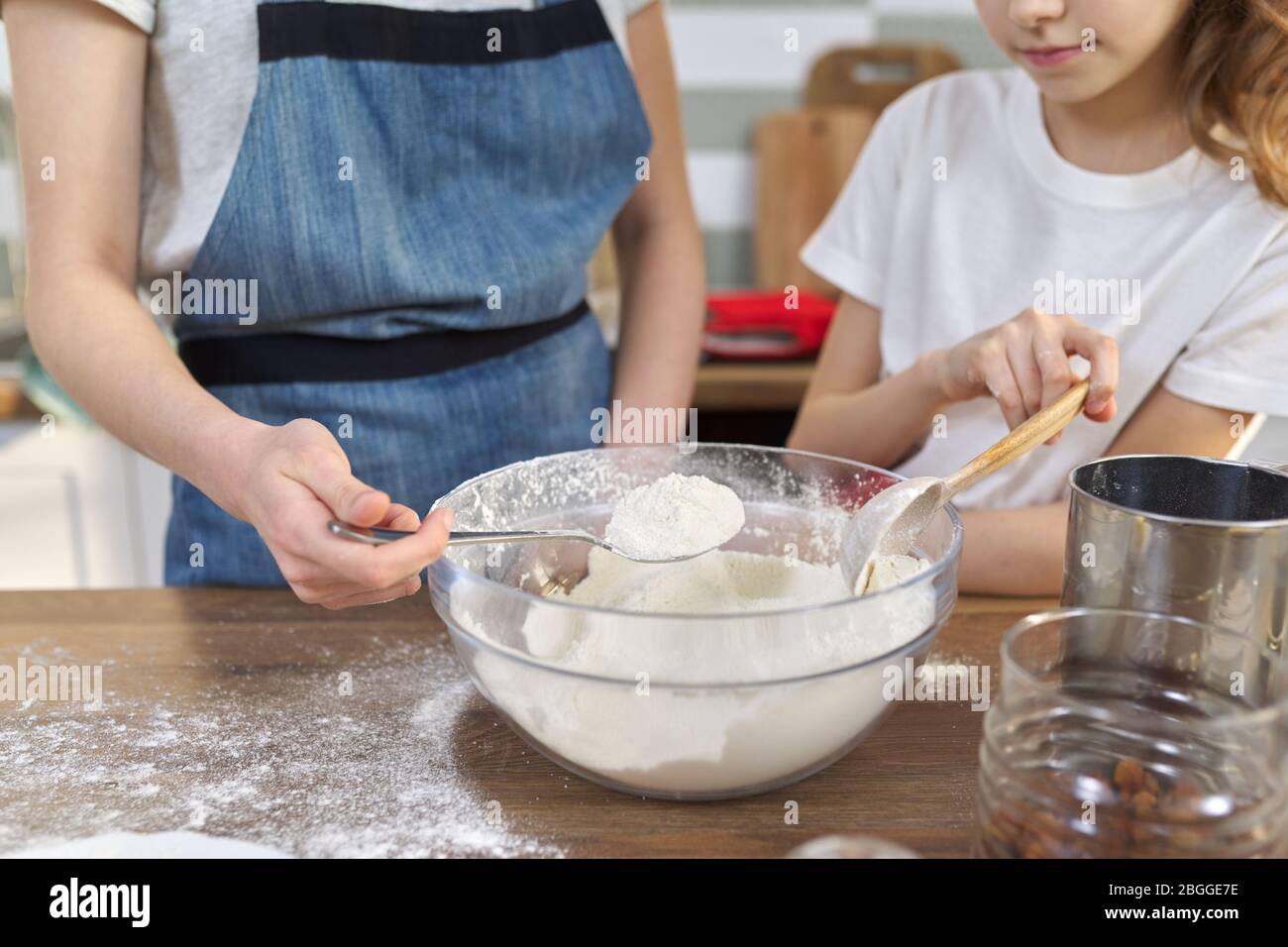 Two girls, teenager and younger sister, preparing cookies together in ...