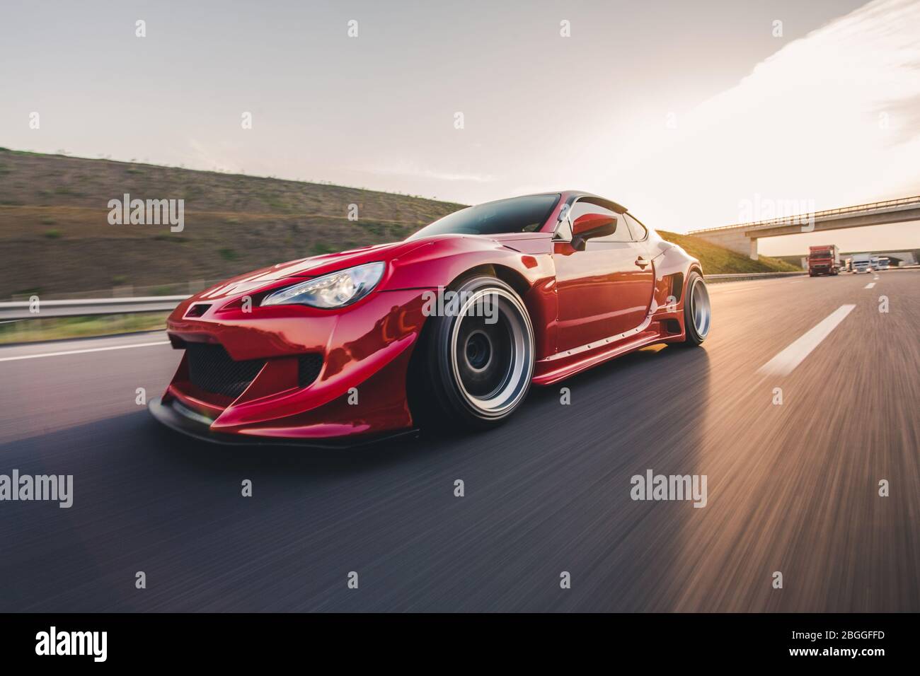 Red racing car on the highway in a sunny day, design lights and wheels ...