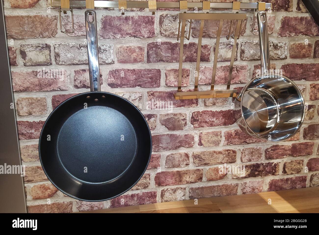 Pans stove hung on brick wall of kitchen Stock Photo - Alamy