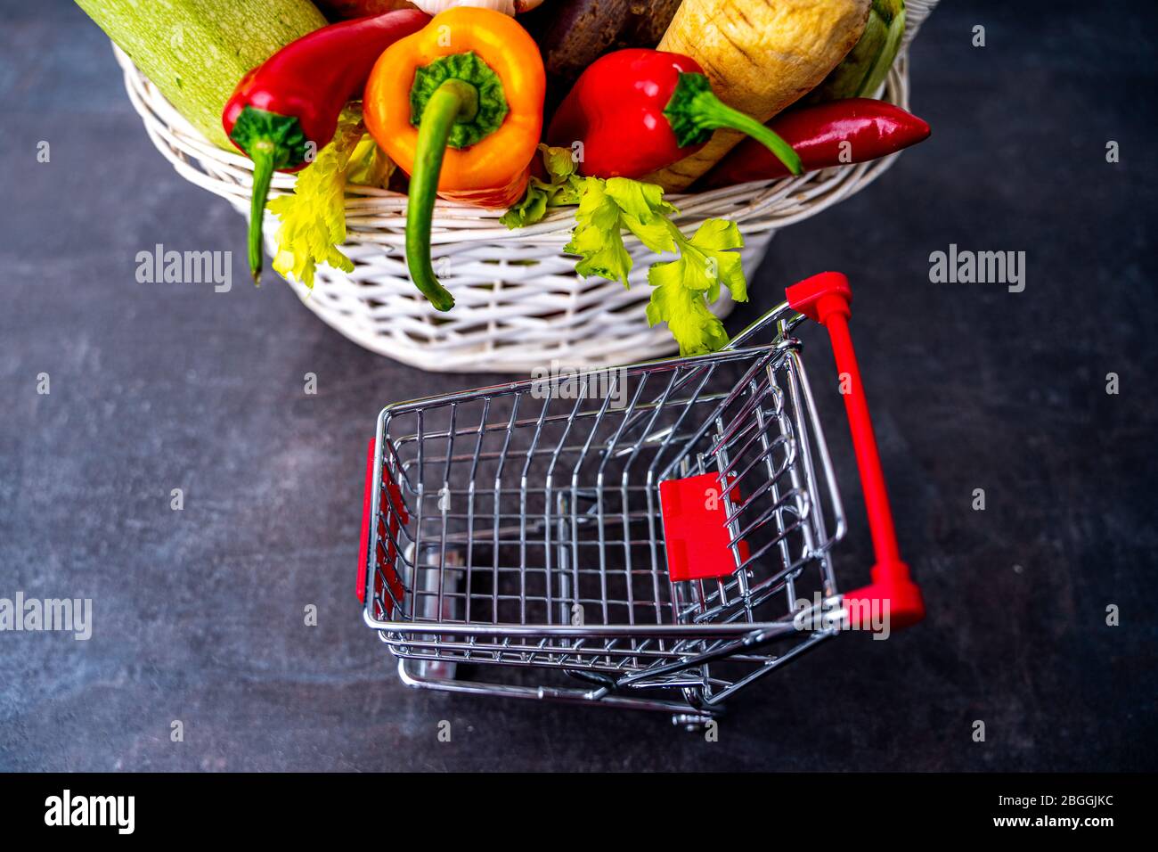 Top view of small shopping cart next to basket with vegetables Stock ...