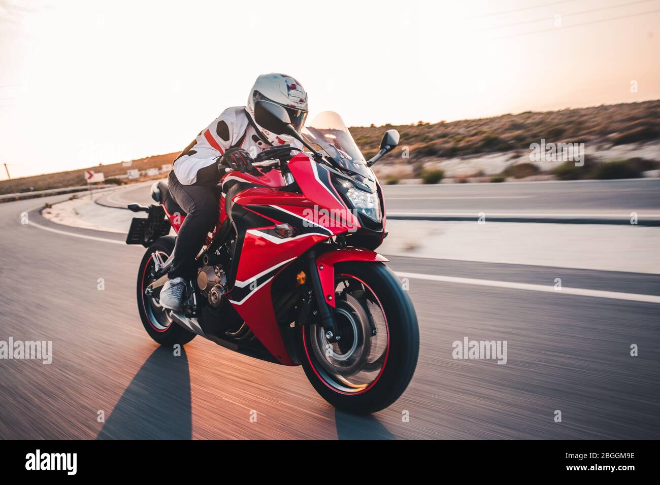 Biking a red motorcycle in the sunset with high speed in helmet and ...