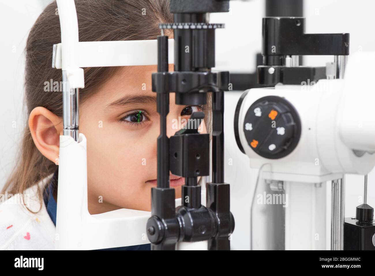 Little girl patient checking vision with special eye equipment. Girl ...
