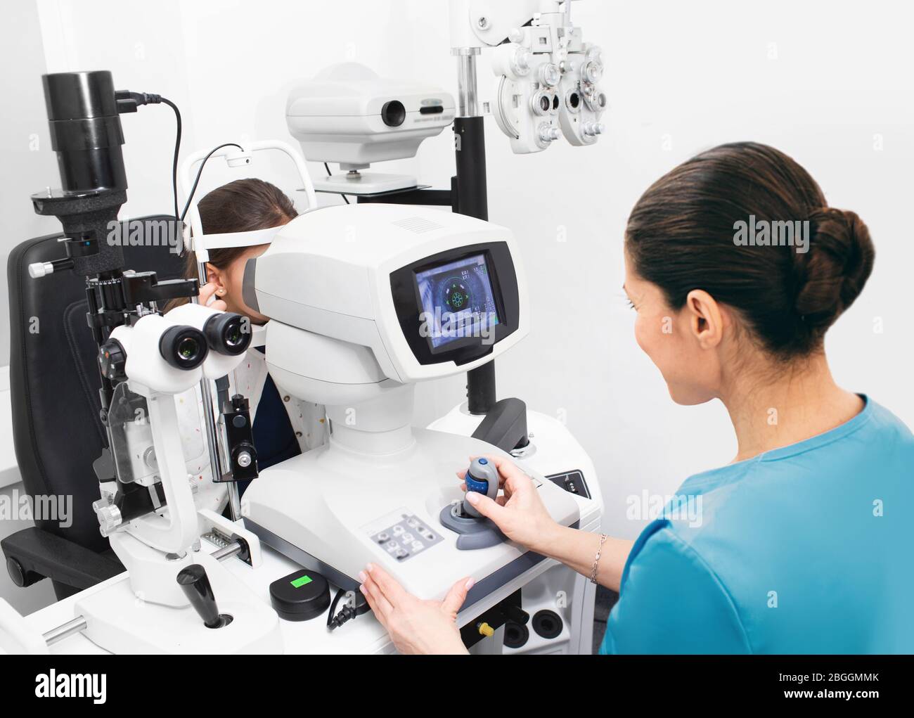 Female doctor checks eyesight of a child on modern equipment in clinic ...