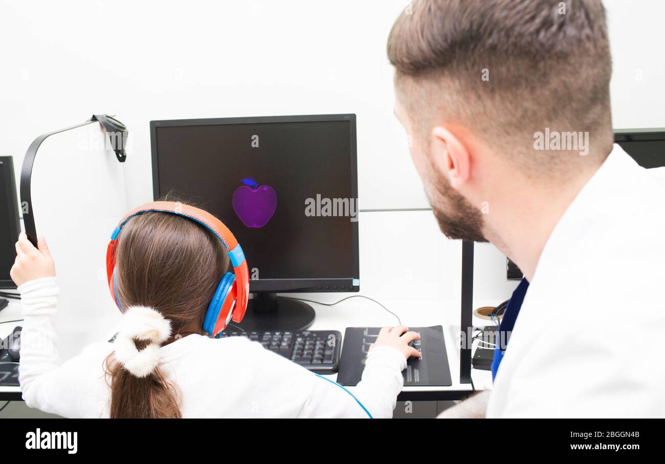 Girl receives strabismus treatment. Amblyopia treatment. Man ...