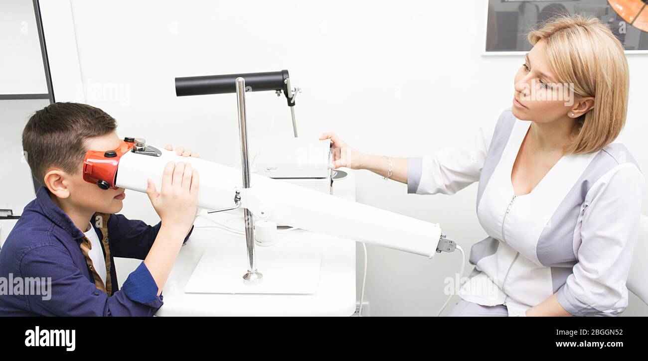 Pleoptics is a treatment for amblyopia. Woman optometrist monitors boy ...