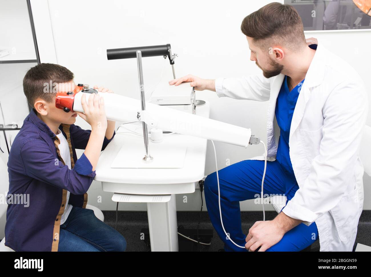 Pleoptics is a treatment for amblyopia. Man optometrist monitors boy's ...