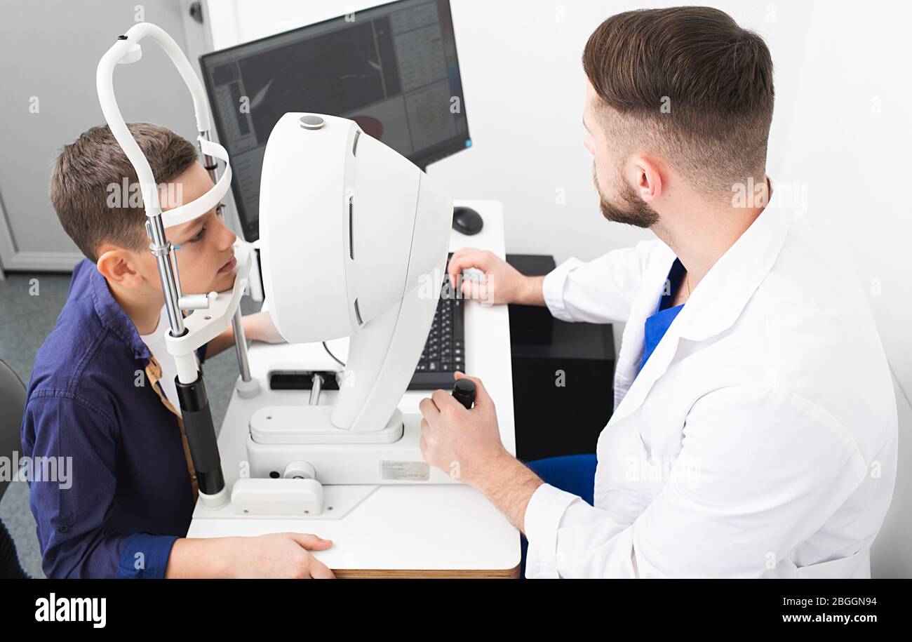 Optometrist man checks the boy's eyesight. Diagnosis of eye anterior ...