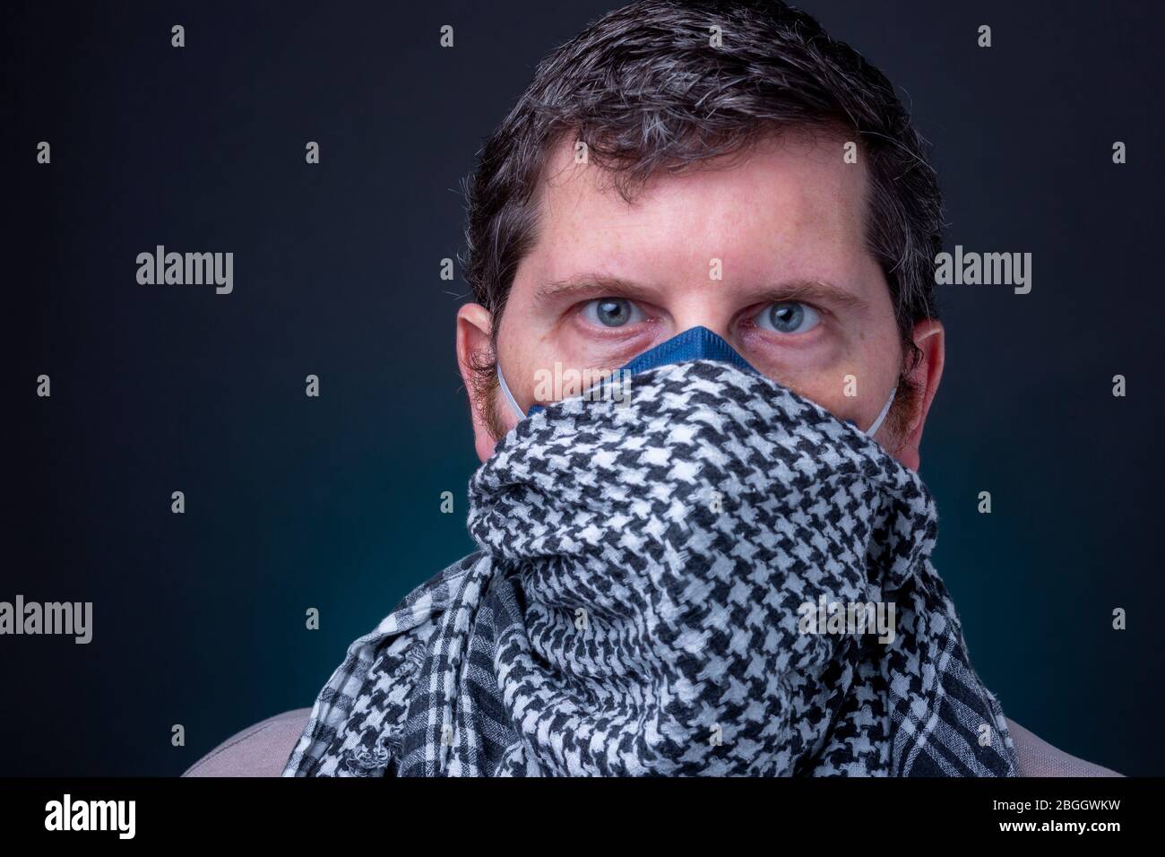 Checker motive scarf over a dark blue respirator face mask on caucasian ...