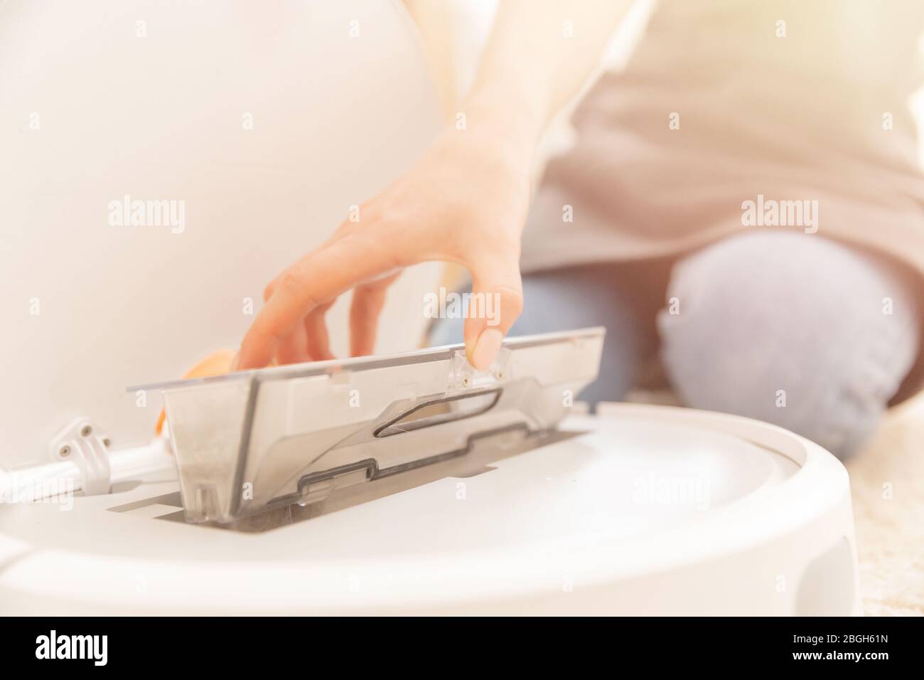 Woman cleans trash bin automatic robot vacuum cleaner Stock Photo - Alamy