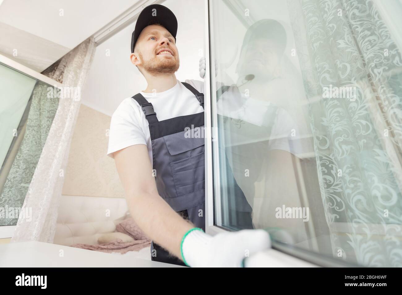 Worker man installs plastic windows and doors with double-glazed white ...