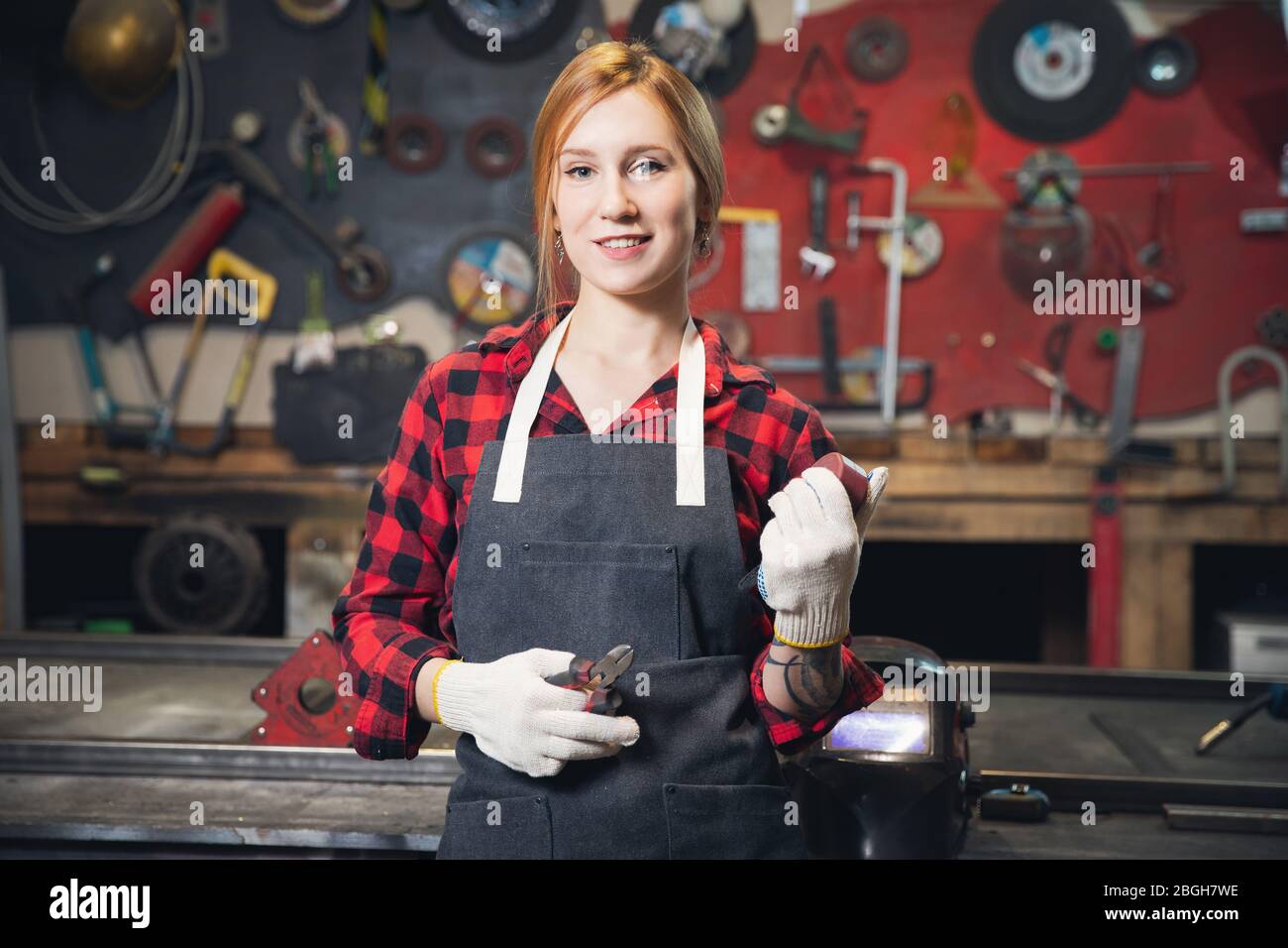 Beautiful young woman craftsman engineer stands in apron on background ...