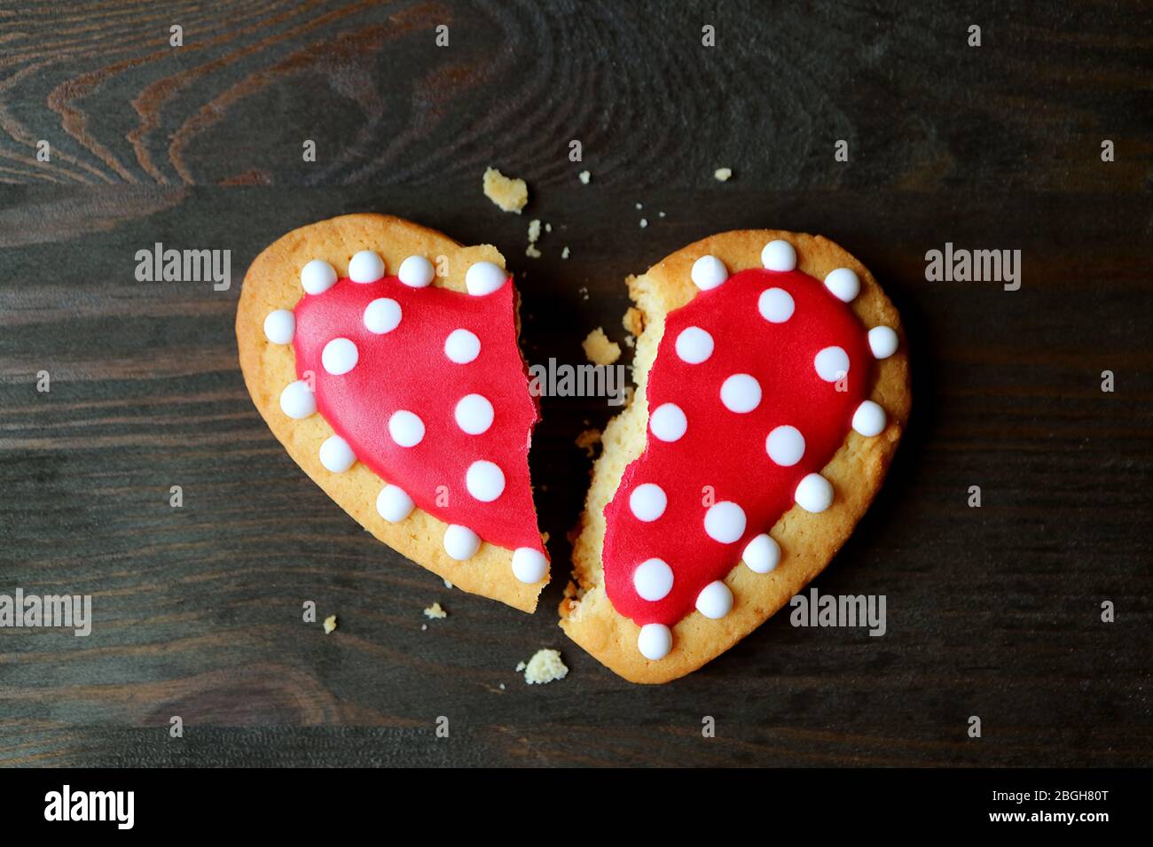 Broken red and white heart shaped royal icing cookie on dark color ...