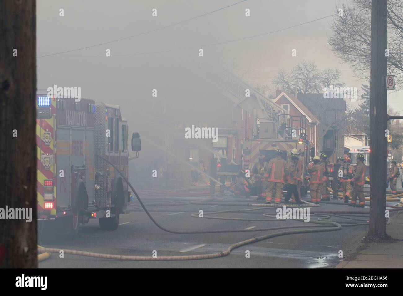 Brigade of firefighters and fire truck battling large structure fire in ...